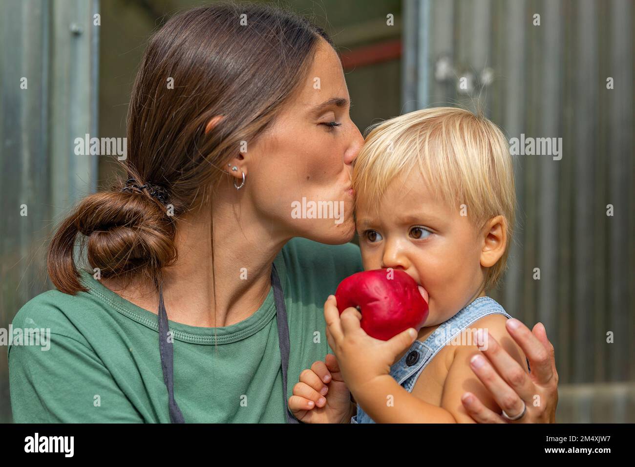 Mother kissing son eating apple in garden Stock Photo - Alamy