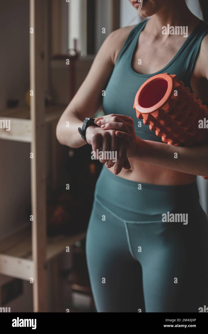 Woman in sports clothing adjusting smart watch standing at home Stock ...