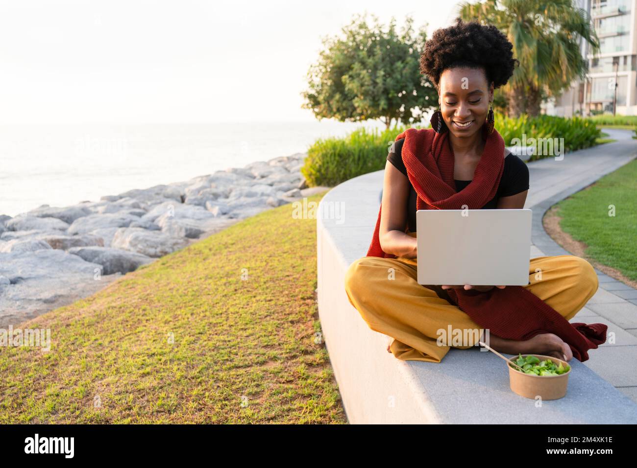 Happy freelancer sitting with laptop on wall Stock Photo - Alamy