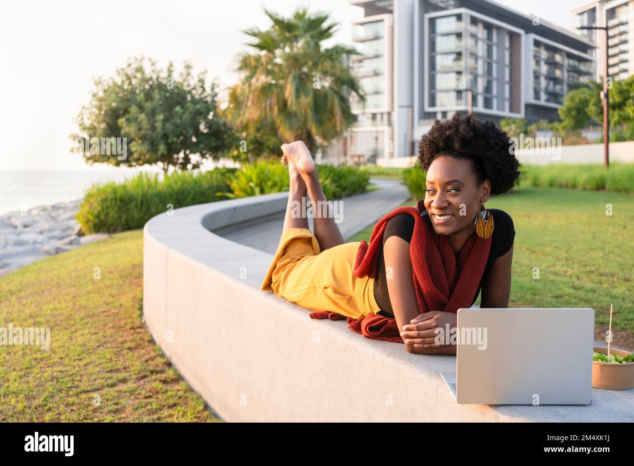 Smiling freelancer lying on wall by laptop Stock Photo - Alamy