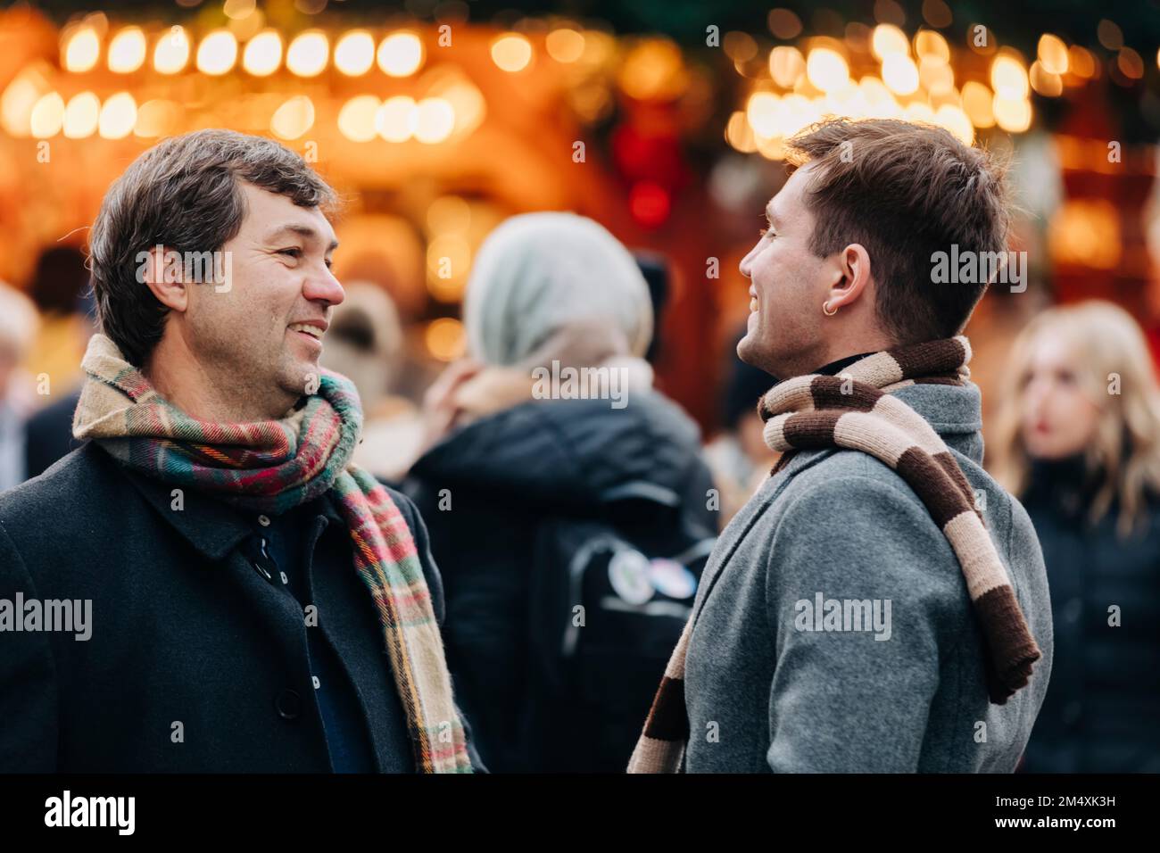 Smiling man talking with father standing at Christmas market Stock ...