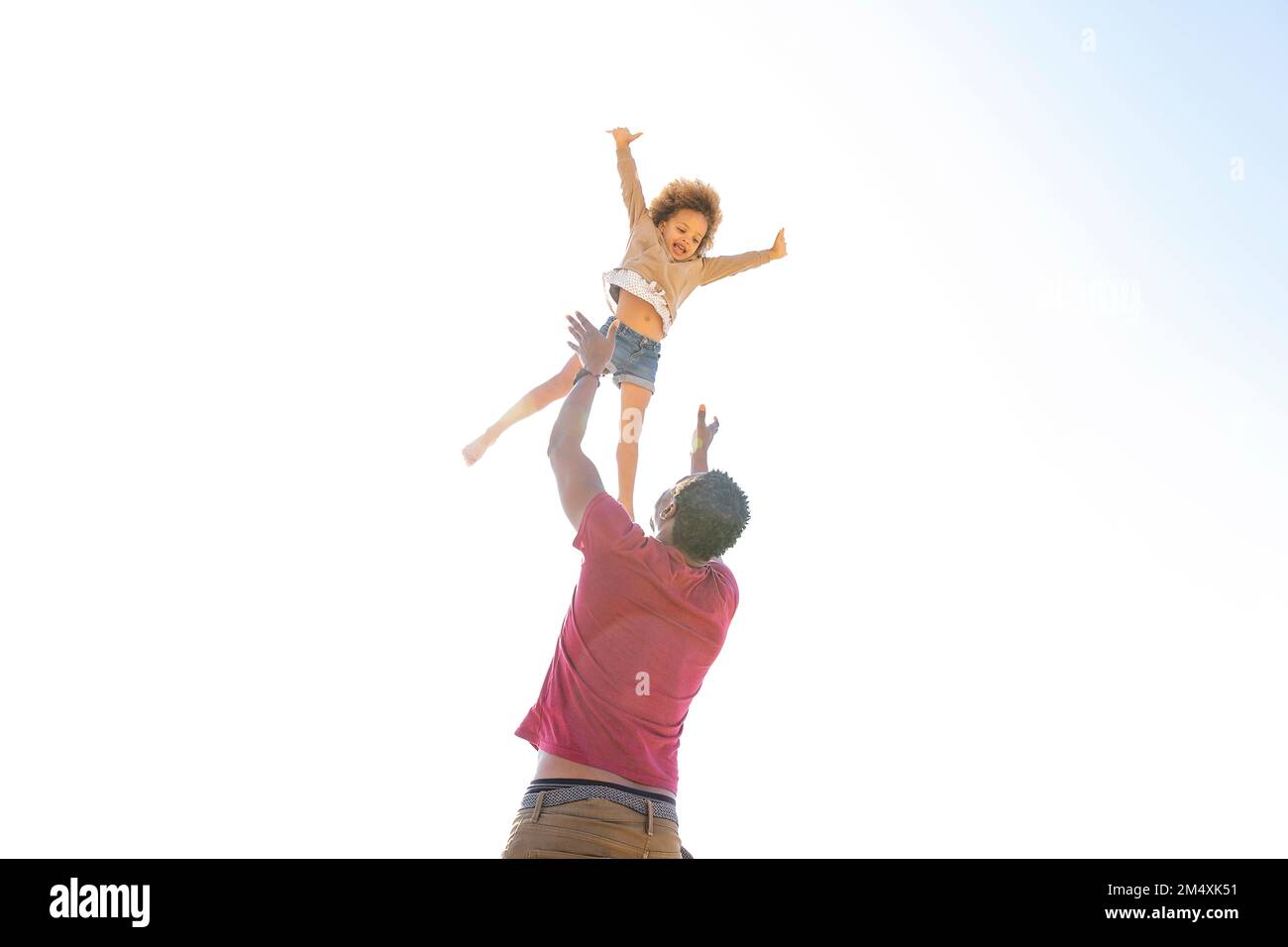 Father catching daughter under clear sky on sunny day Stock Photo - Alamy