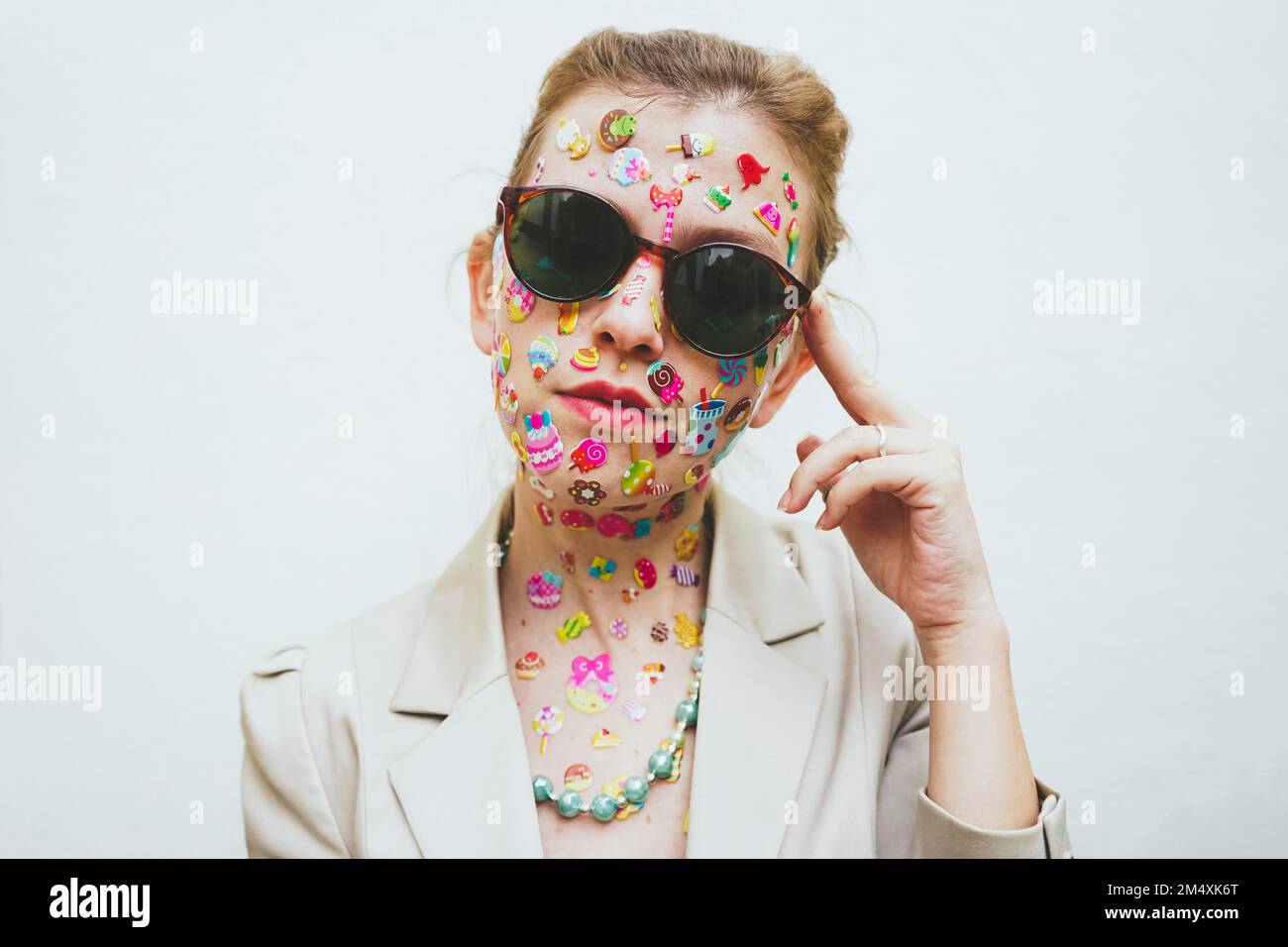Woman with stickers on face wearing sunglasses in front of white ...