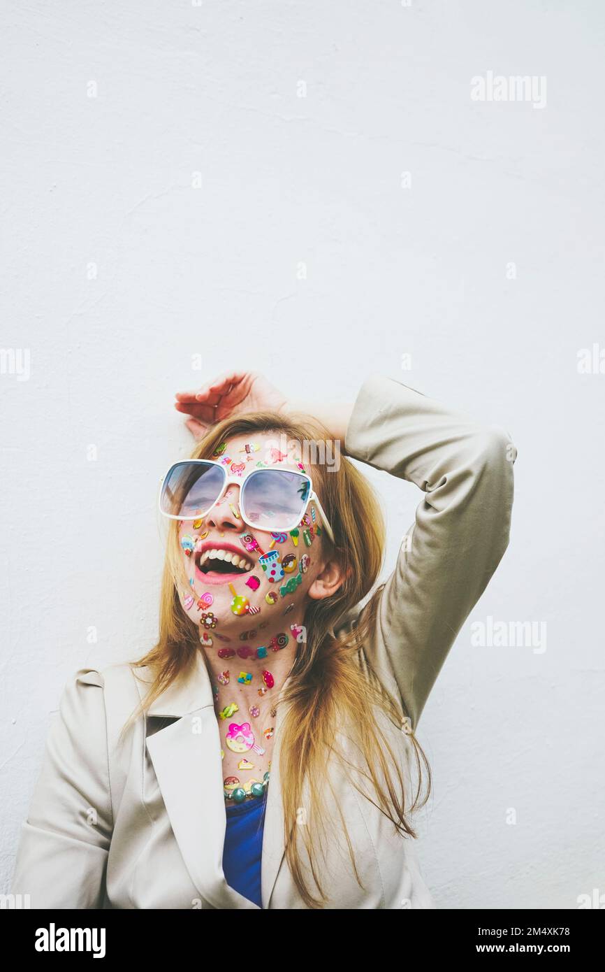Happy woman with stickers on face enjoying in front of white background ...