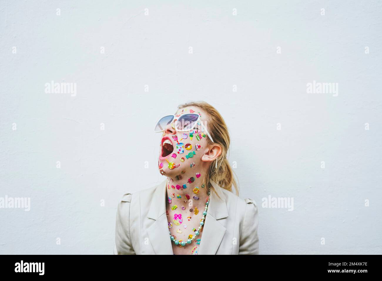 Woman with stickers on face screaming in front of white background ...