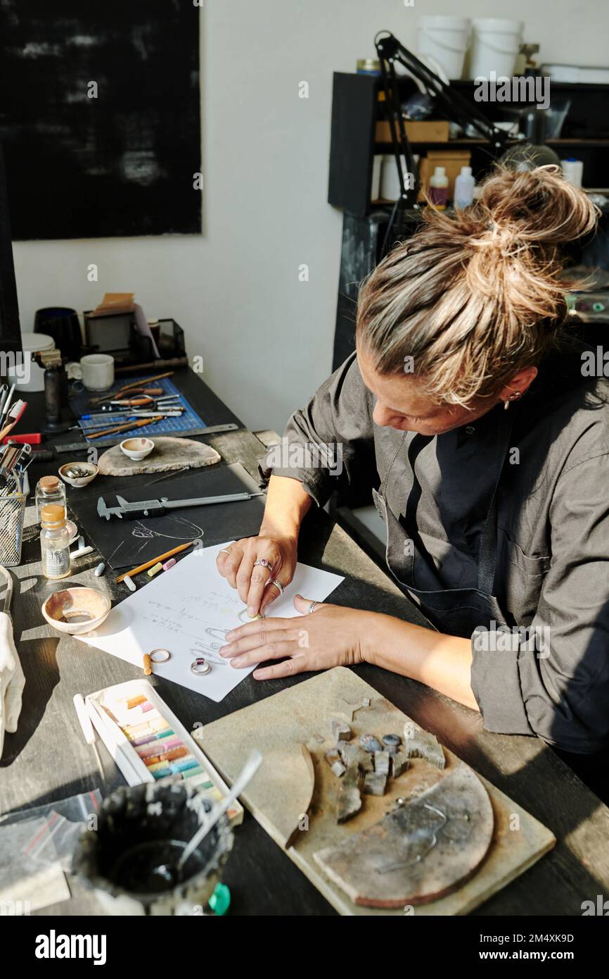 Craftswoman sketching ring design on paper at workbench Stock Photo - Alamy