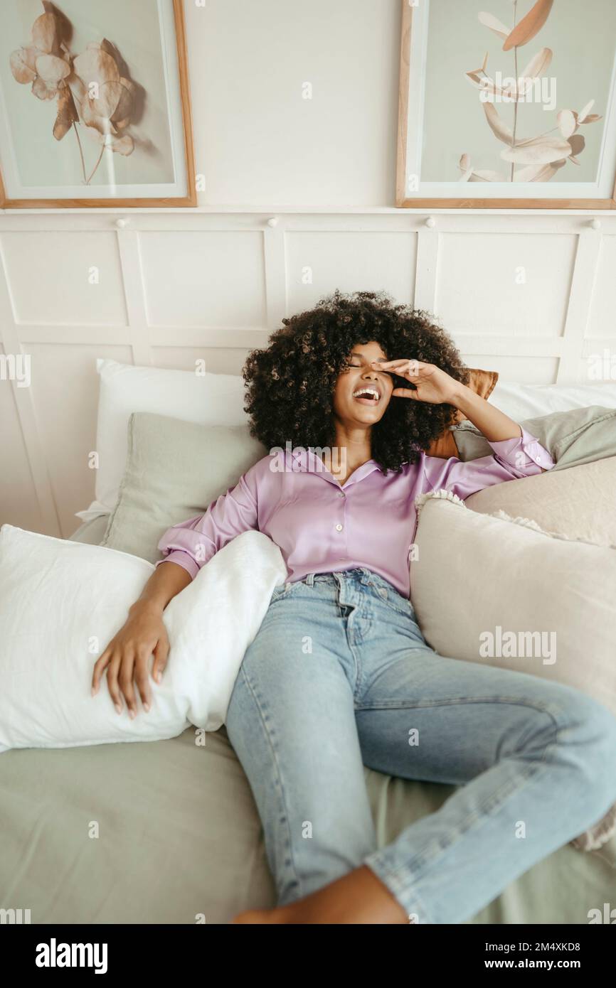 Young woman lying on bed laughing at home Stock Photo - Alamy