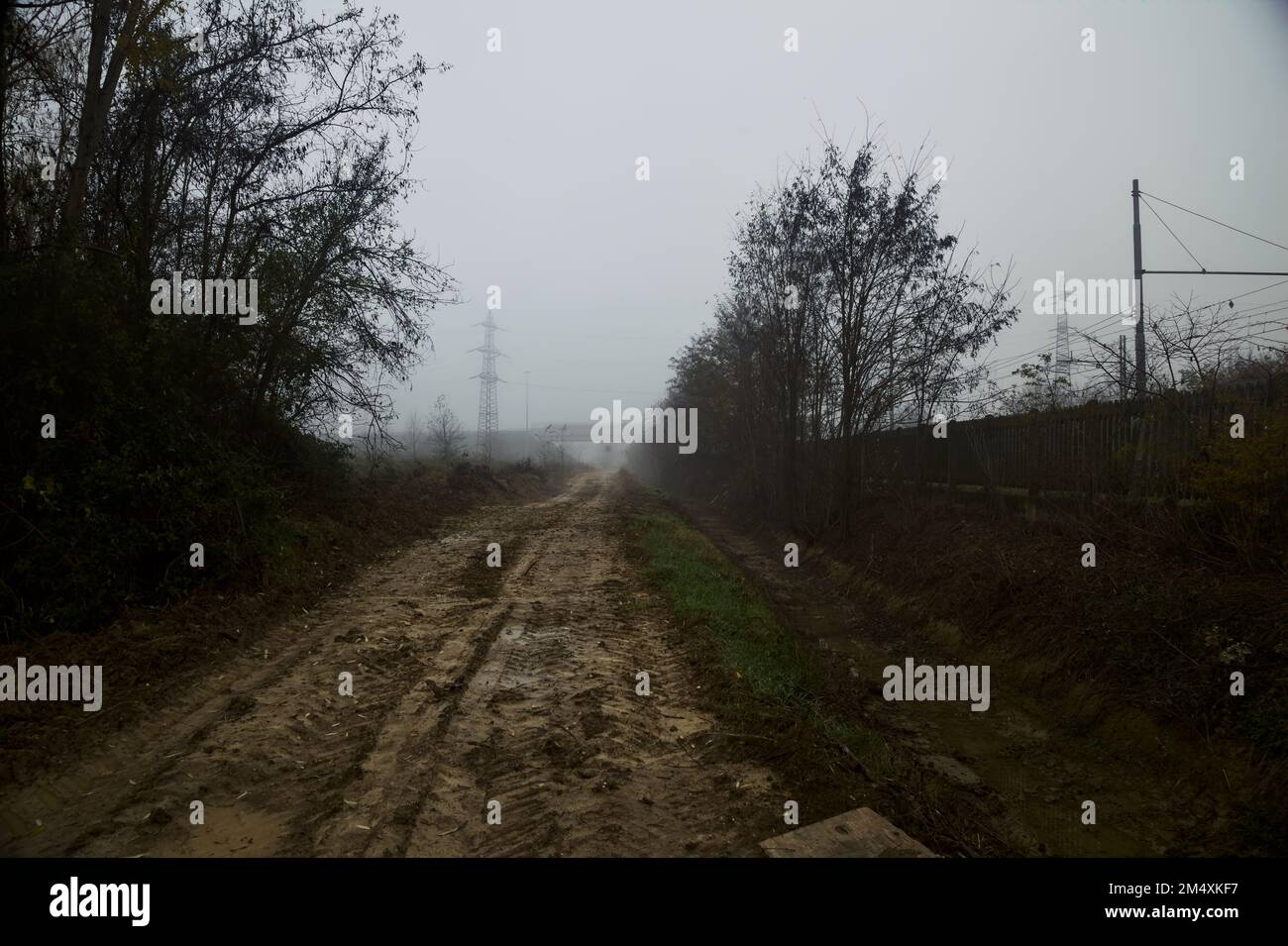 Muddy road next to a railroad track on a foggy day in the italian ...