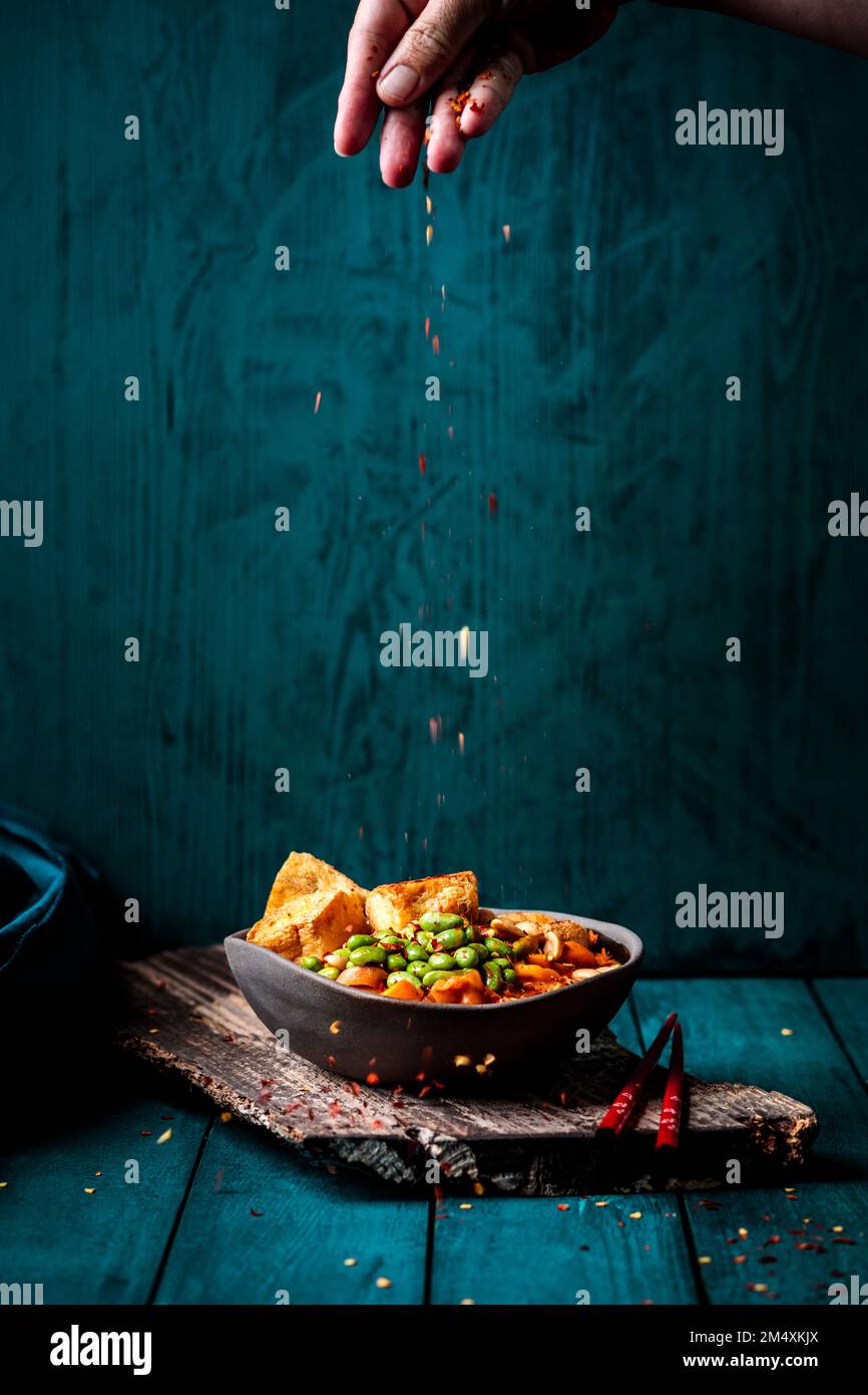 Hand of person pouring spices into bowl of vegan curry Stock Photo - Alamy