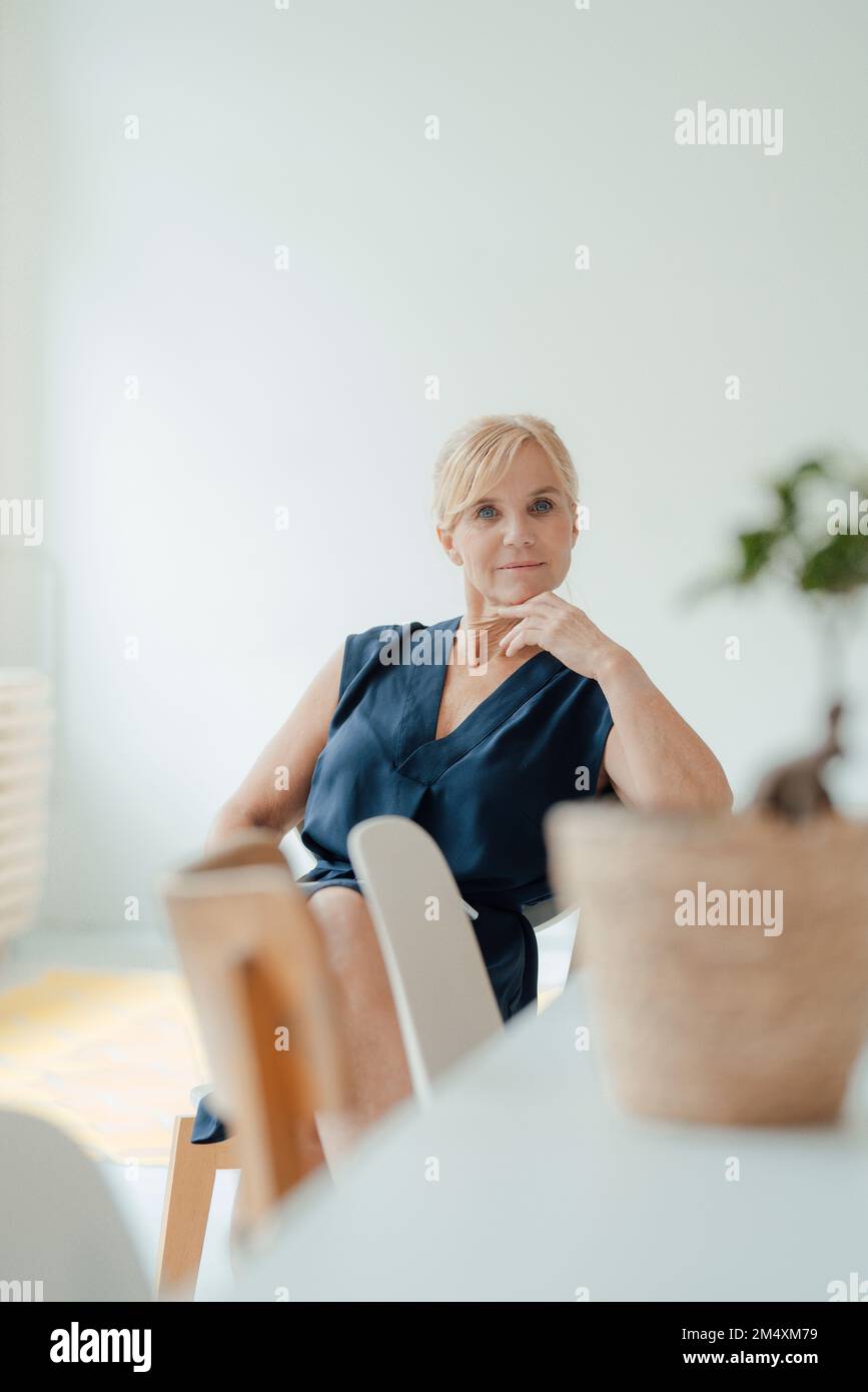 Mature businesswoman with hand on chin in front of white wall Stock ...