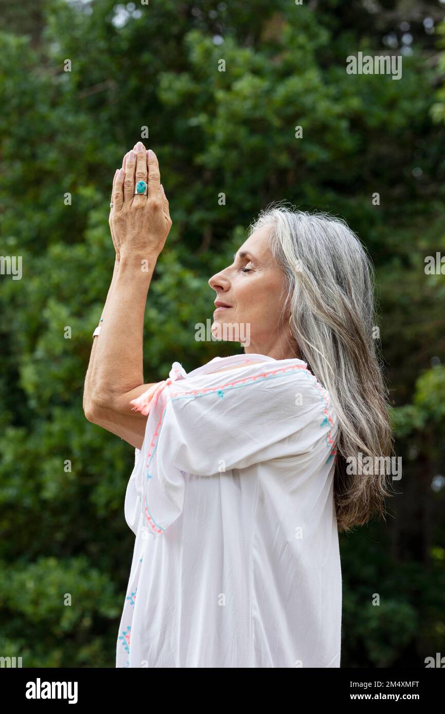 Mature woman meditating with hands clasped in forest Stock Photo - Alamy