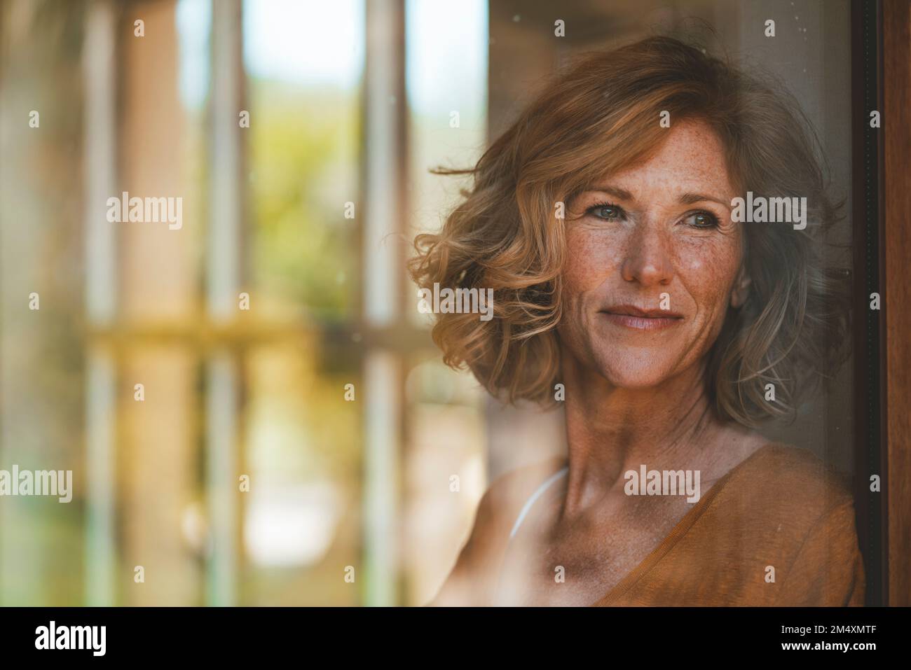 Thoughtful mature woman seen through glass window Stock Photo - Alamy