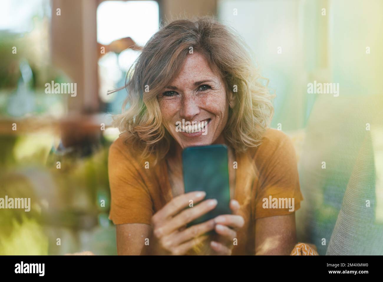 Happy woman with smart phone seen through glass of home Stock Photo - Alamy