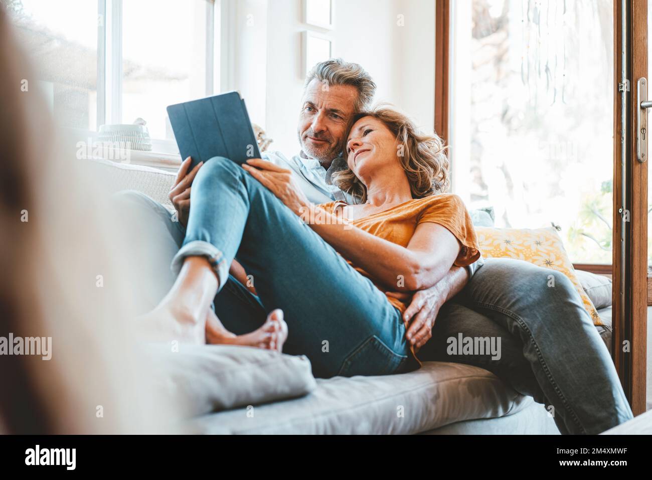 Loving mature couple using tablet computer on sofa in living room Stock ...