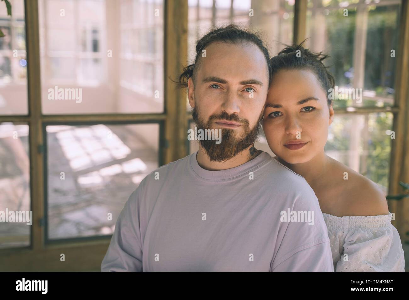 Confident couple standing in front of window Stock Photo - Alamy