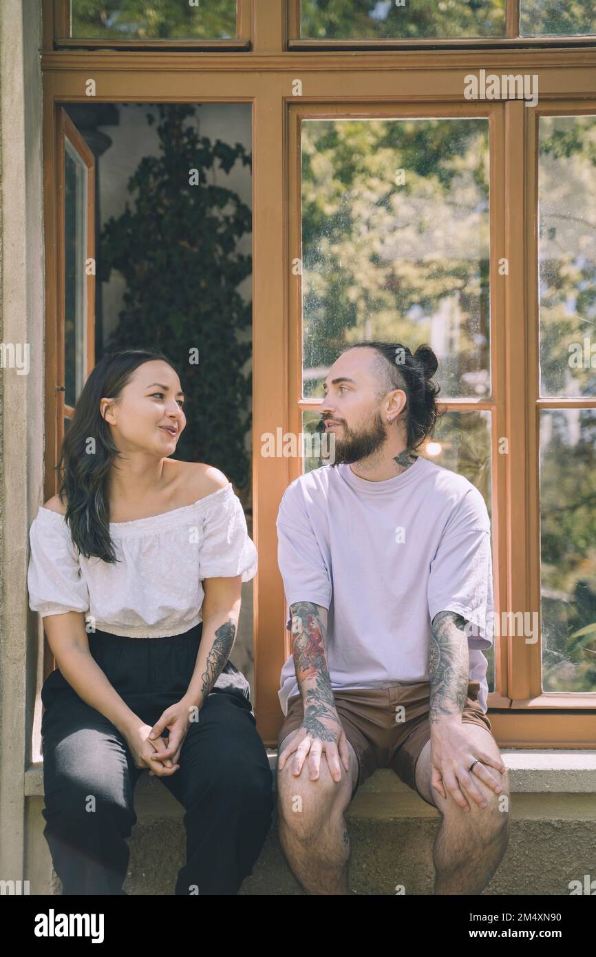Woman talking with hipster boyfriend sitting on window sill Stock Photo ...