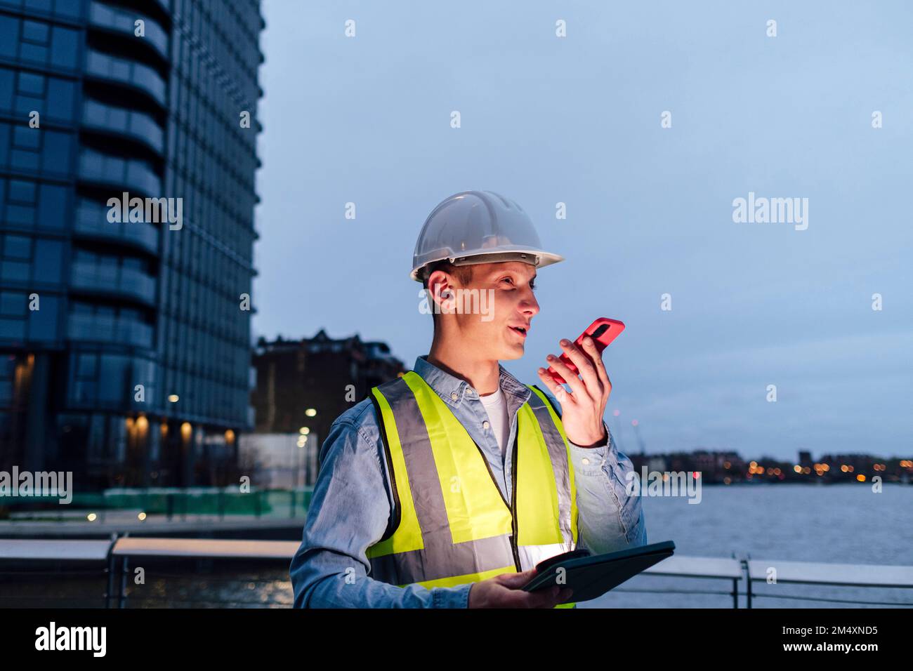 Engineer talking over speaker of mobile phone holding tablet PC Stock ...