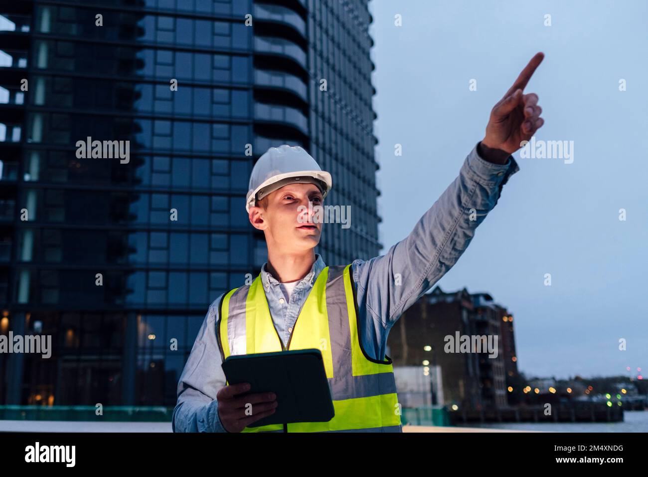 Engineer holding tablet PC pointing in front of building Stock Photo ...