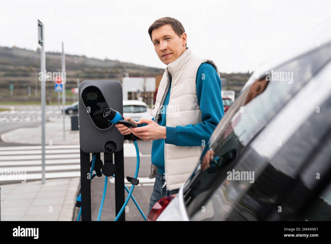 Man with smart phone and charger standing at charging station Stock ...