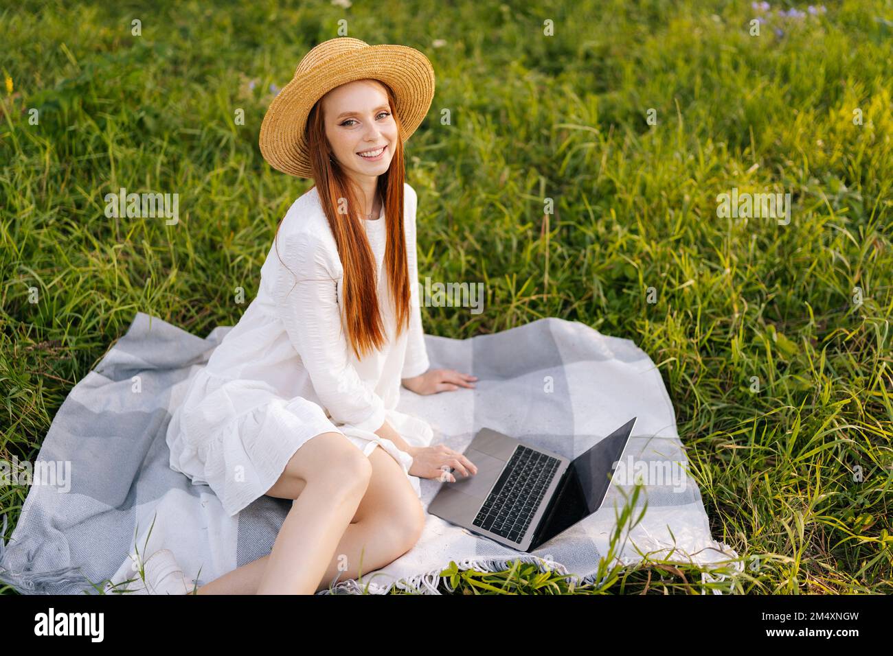 High-angle view of cheerful young redhead freelancer in straw hat and ...