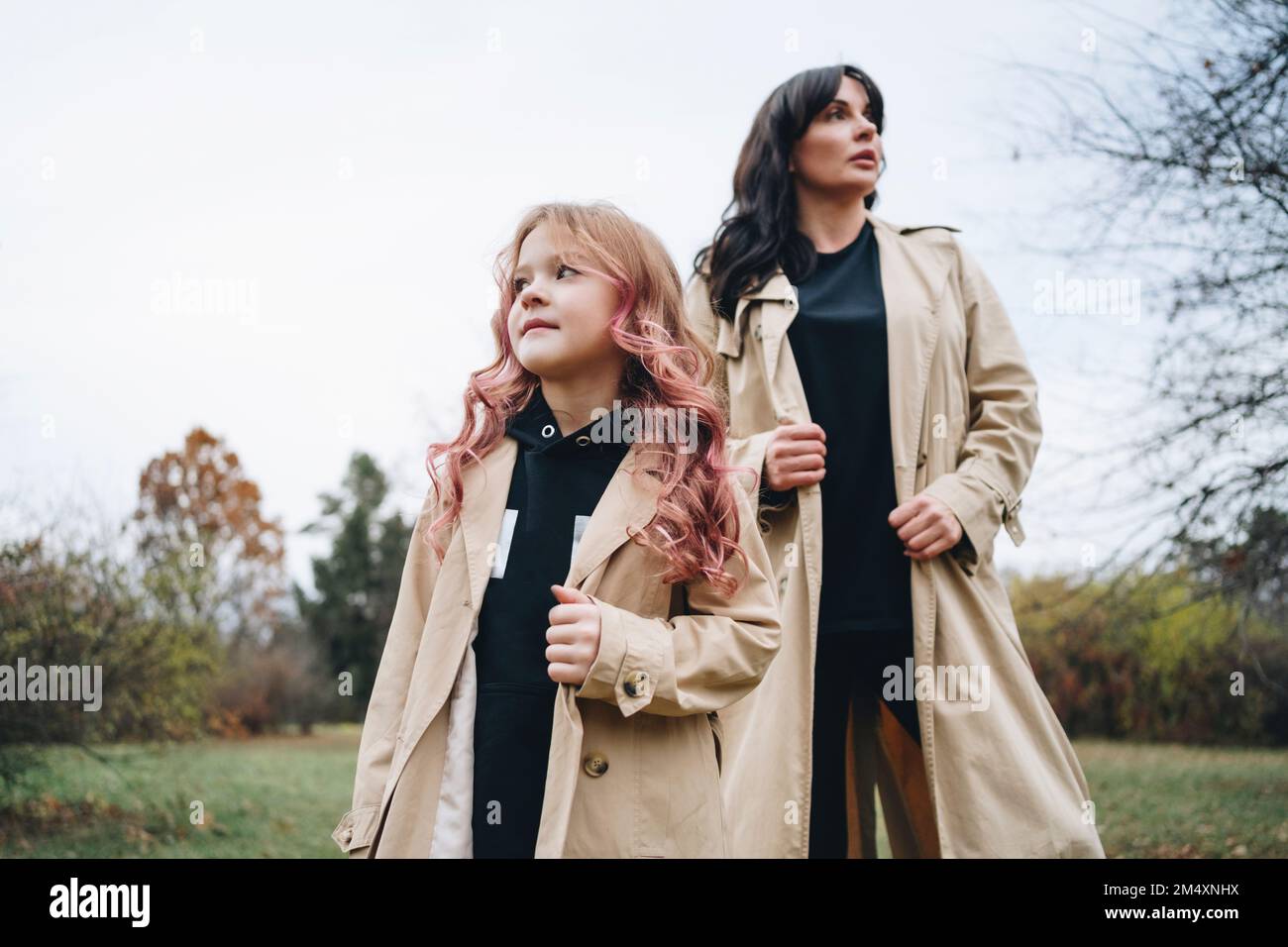 Girl and mother wearing trench coat at park Stock Photo - Alamy
