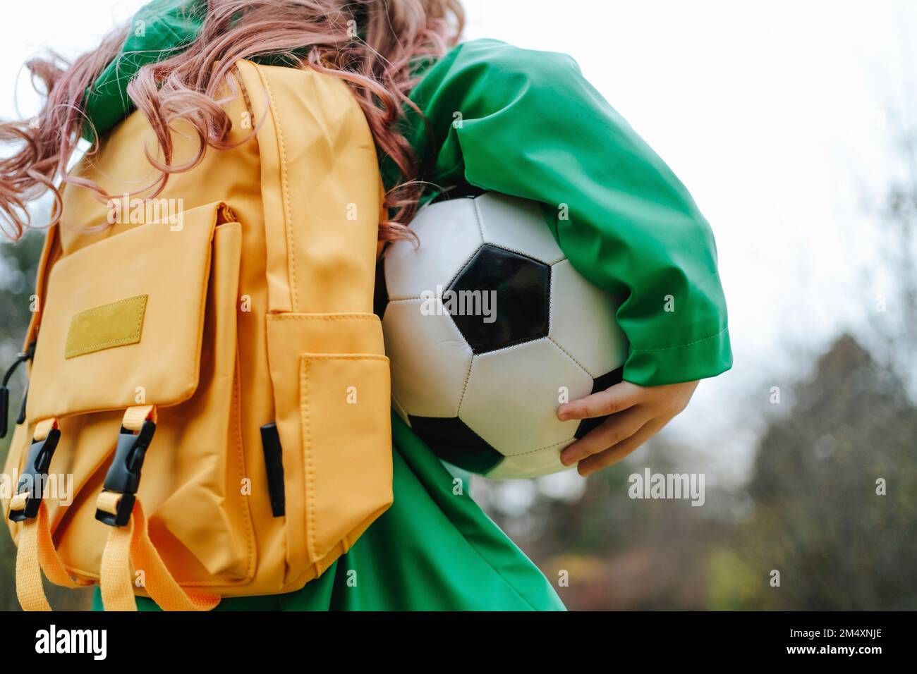 Girl with yellow backpack and soccer ball at park Stock Photo - Alamy