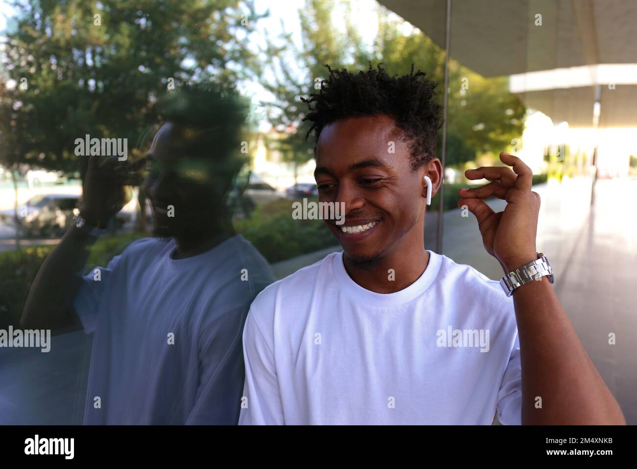 Happy man gesturing and enjoying music through in-ear headphones near ...