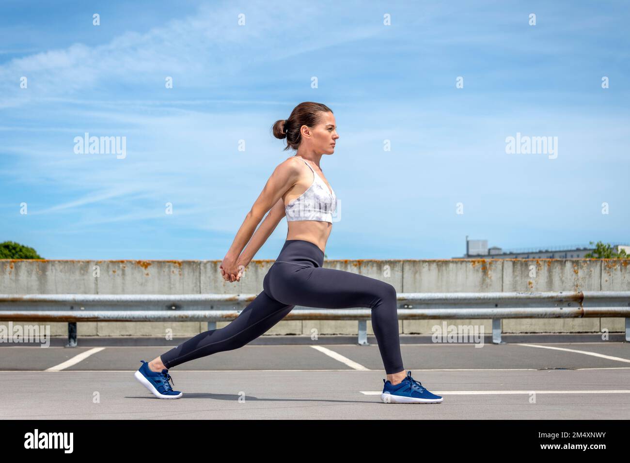 sporty fit woman doing stretching exercise outside in the sun, urban ...