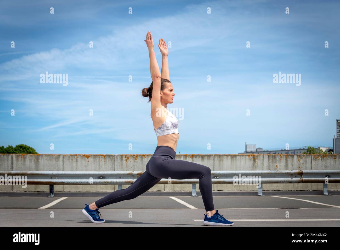Sporty fit woman doing stretching exercise outside in the sun, urban ...