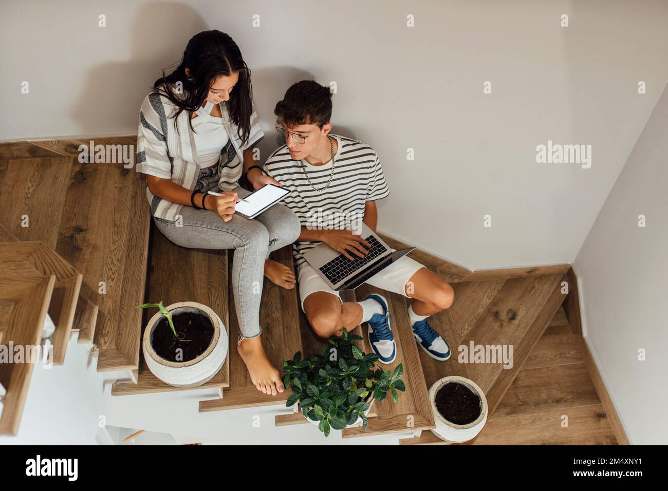 Sibling studying together through tablet PC sitting on staircase at ...