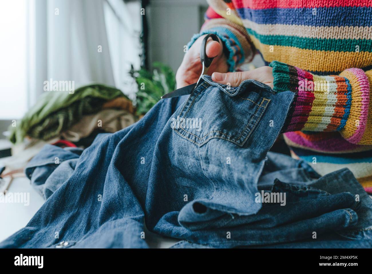 Hands of fashion designer cutting denim jeans Stock Photo - Alamy