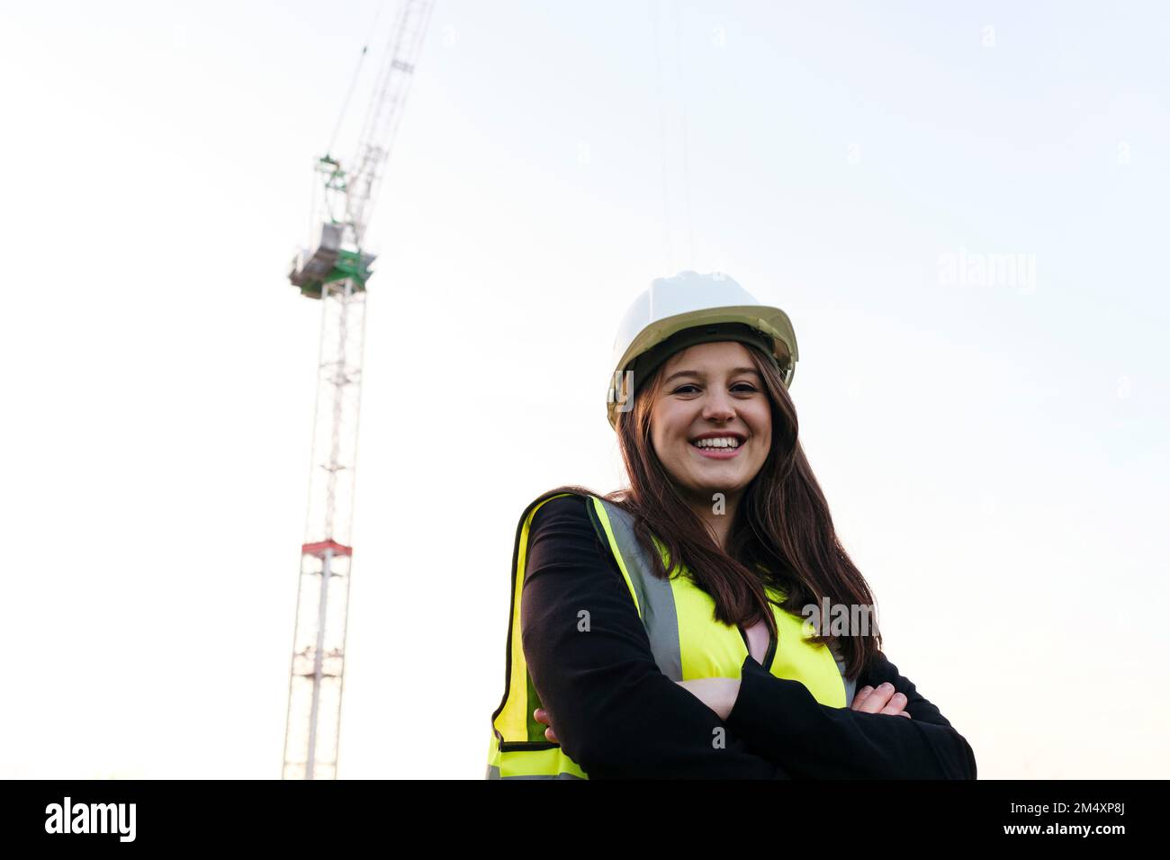 Happy female engineer with arms crossed under clear sky Stock Photo - Alamy