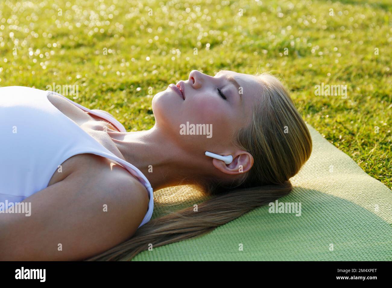 Woman with eyes closed lying on exercise mat Stock Photo - Alamy