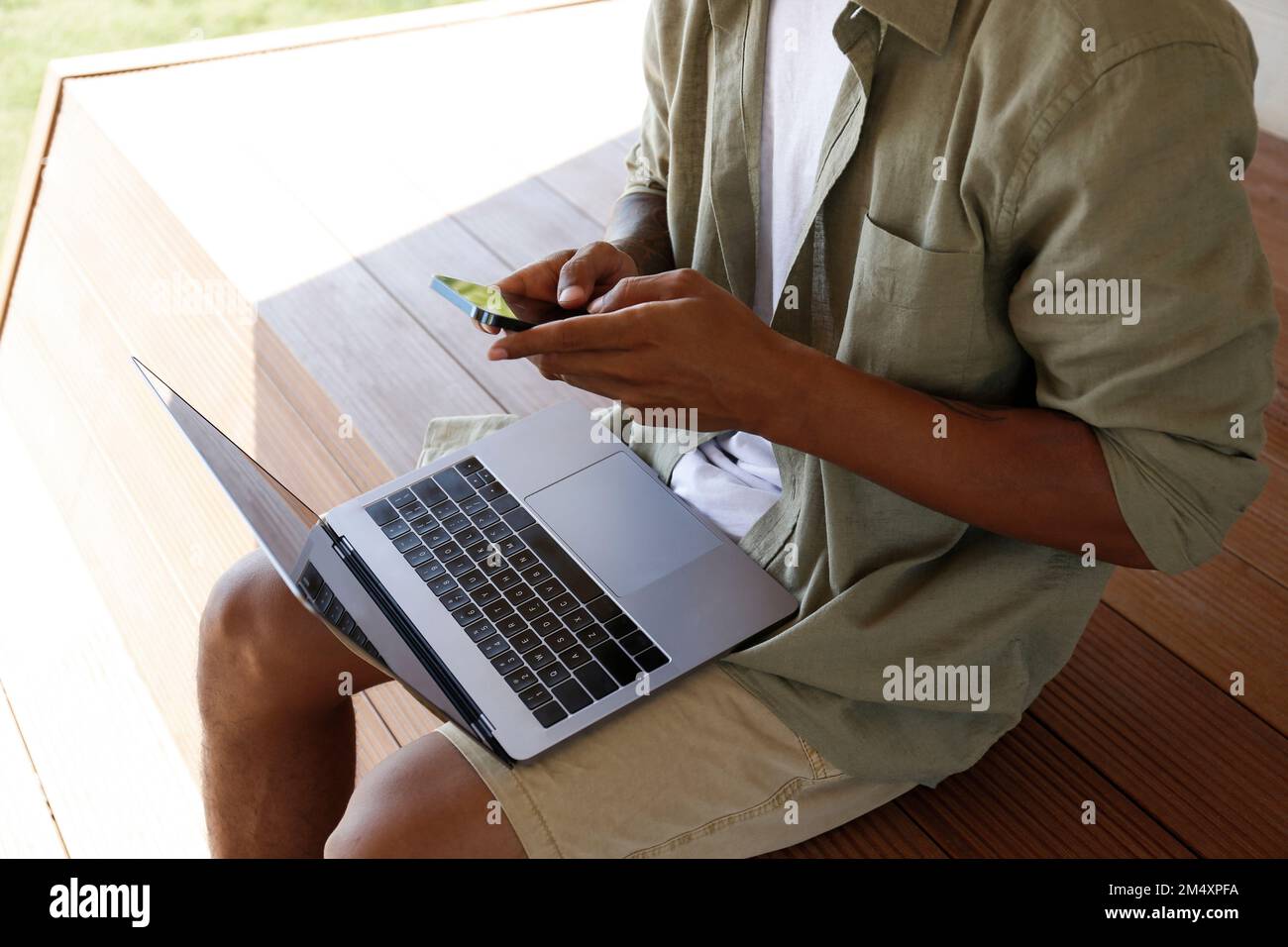 Hands of freelancer using smart phone sitting with laptop on lap Stock ...