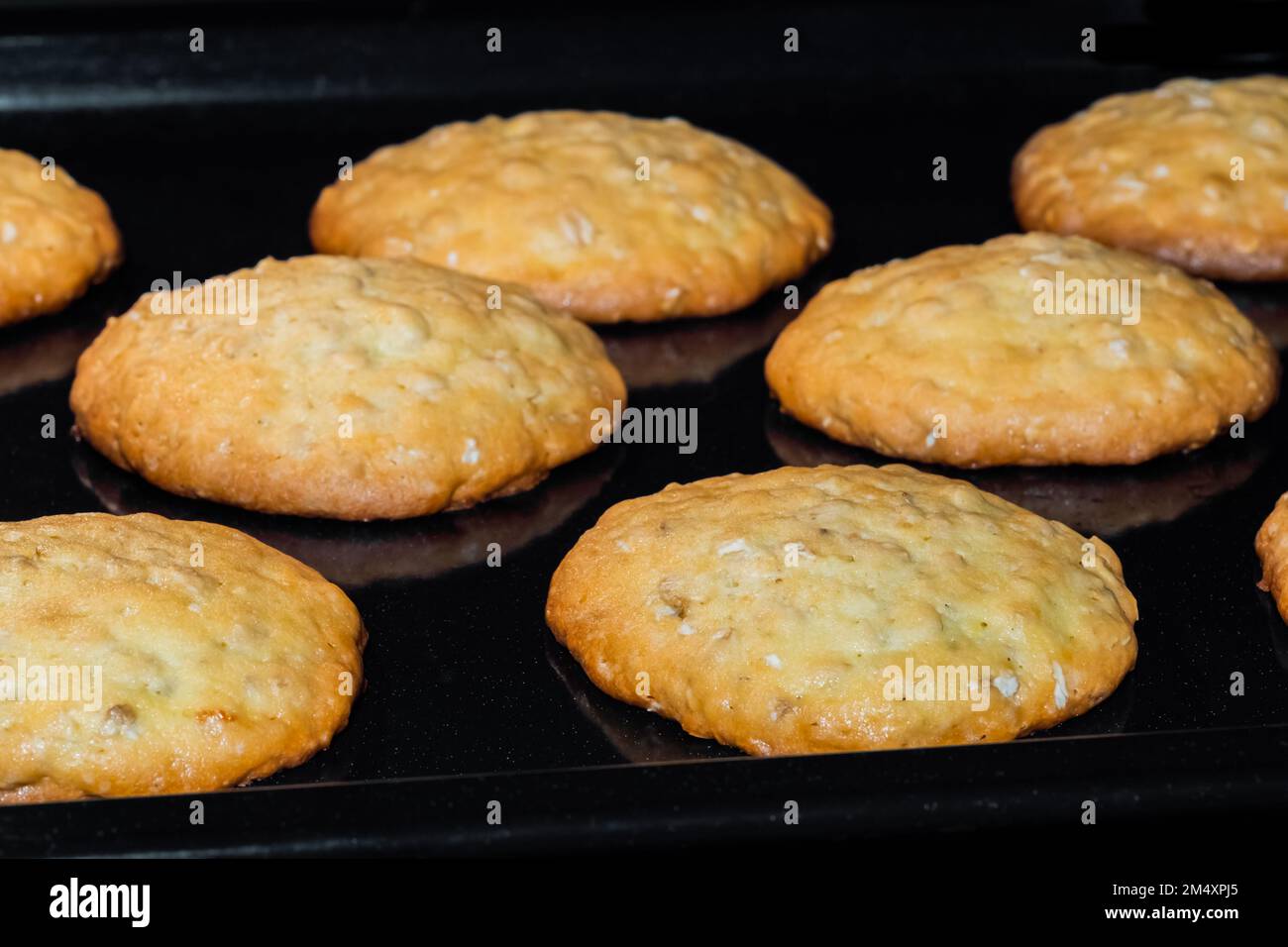 Many baked homemade crunchy oatmeal cookies on metal sheet in oven ...