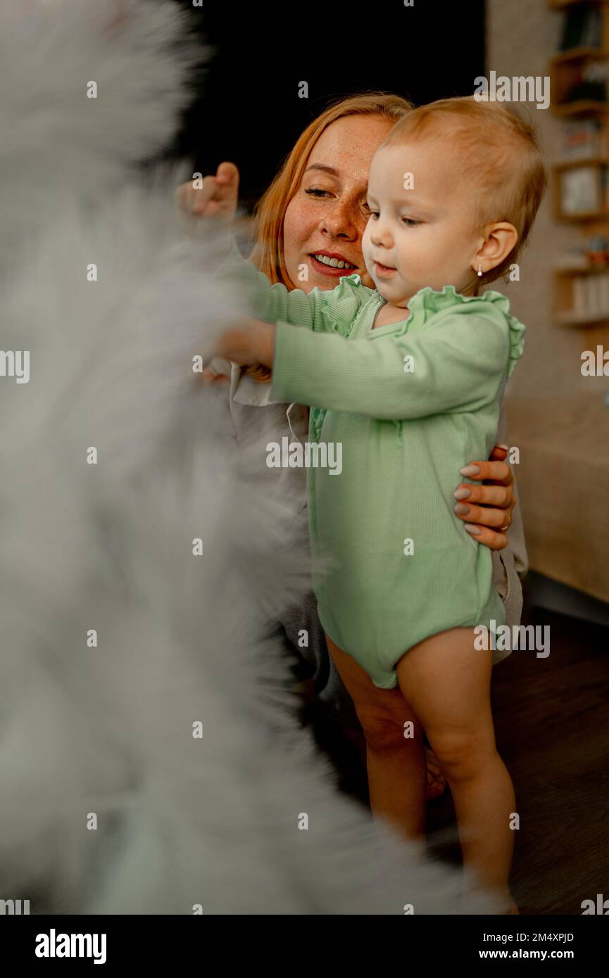 Happy mother with cute daughter decorating Christmas tree at home Stock ...