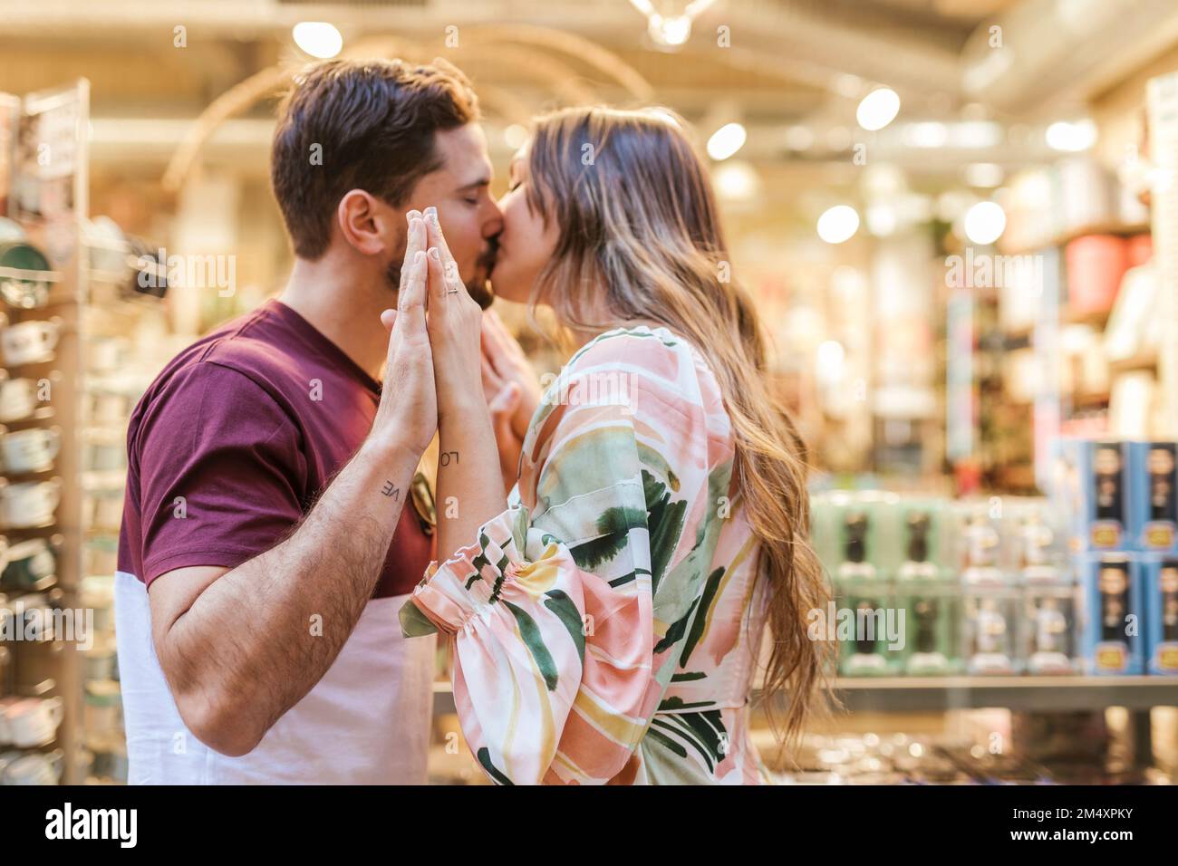 Affectionate man and woman kissing each other in store Stock Photo - Alamy
