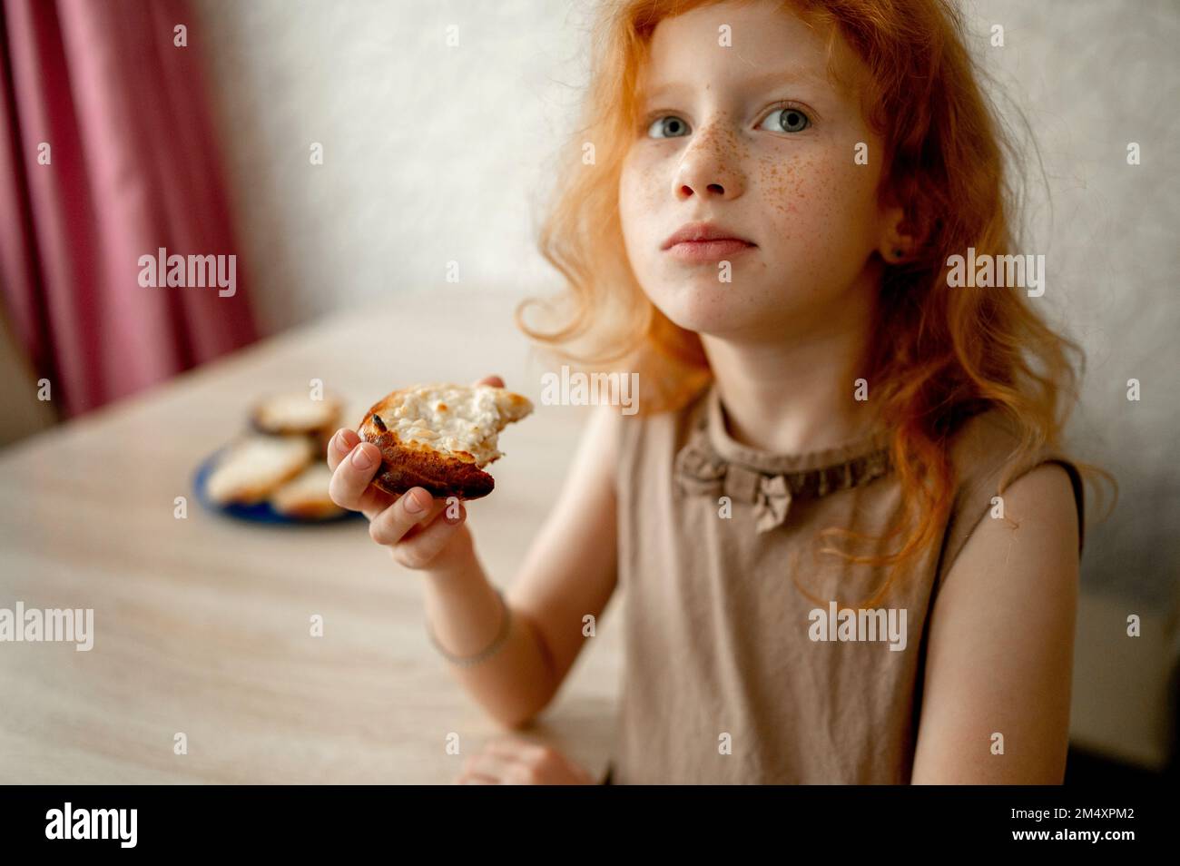 Redhead girl eating cheesecake at table Stock Photo - Alamy