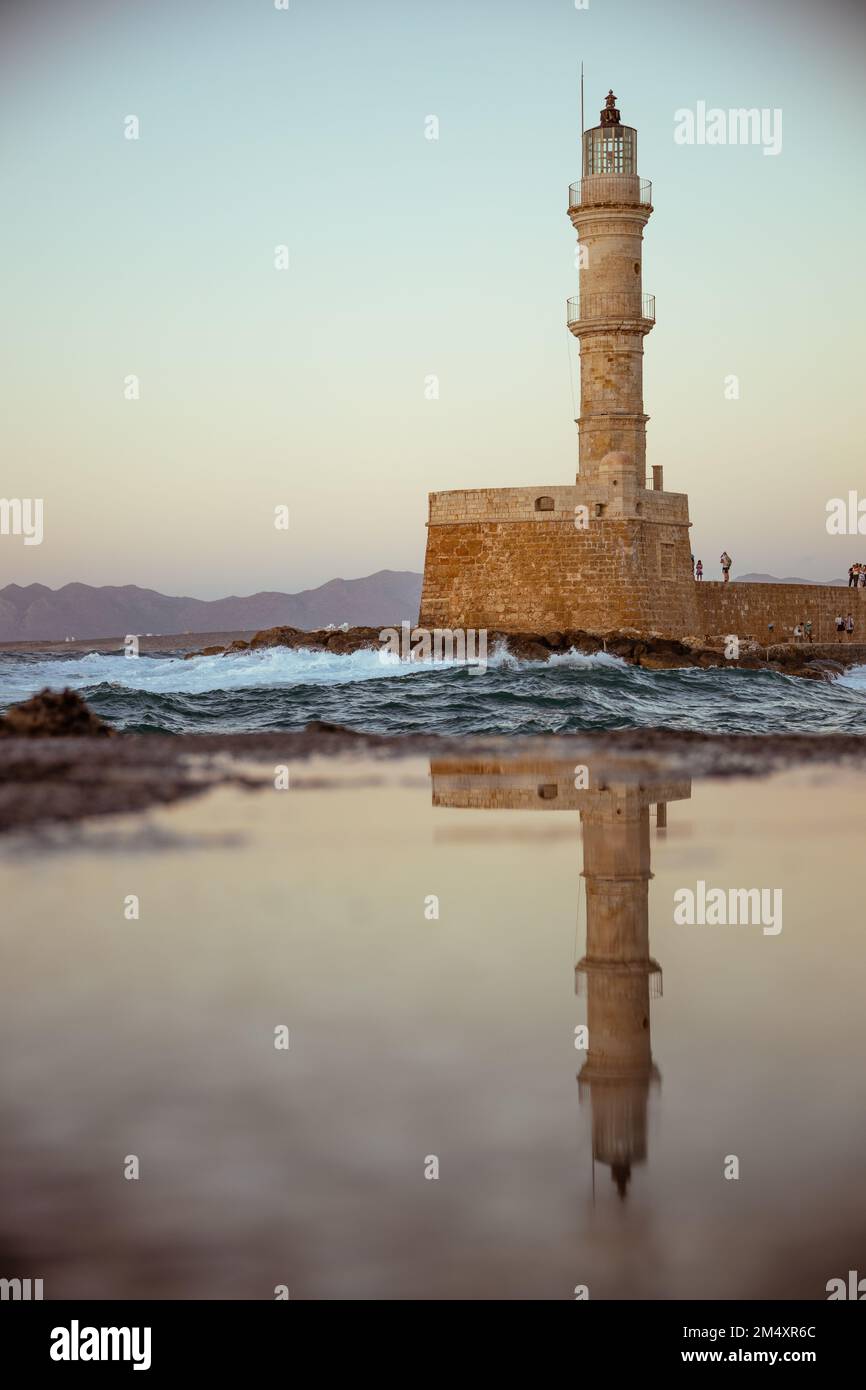 A vertical shot of the Chania Lighthouse in Crete, Greece reflecting on ...