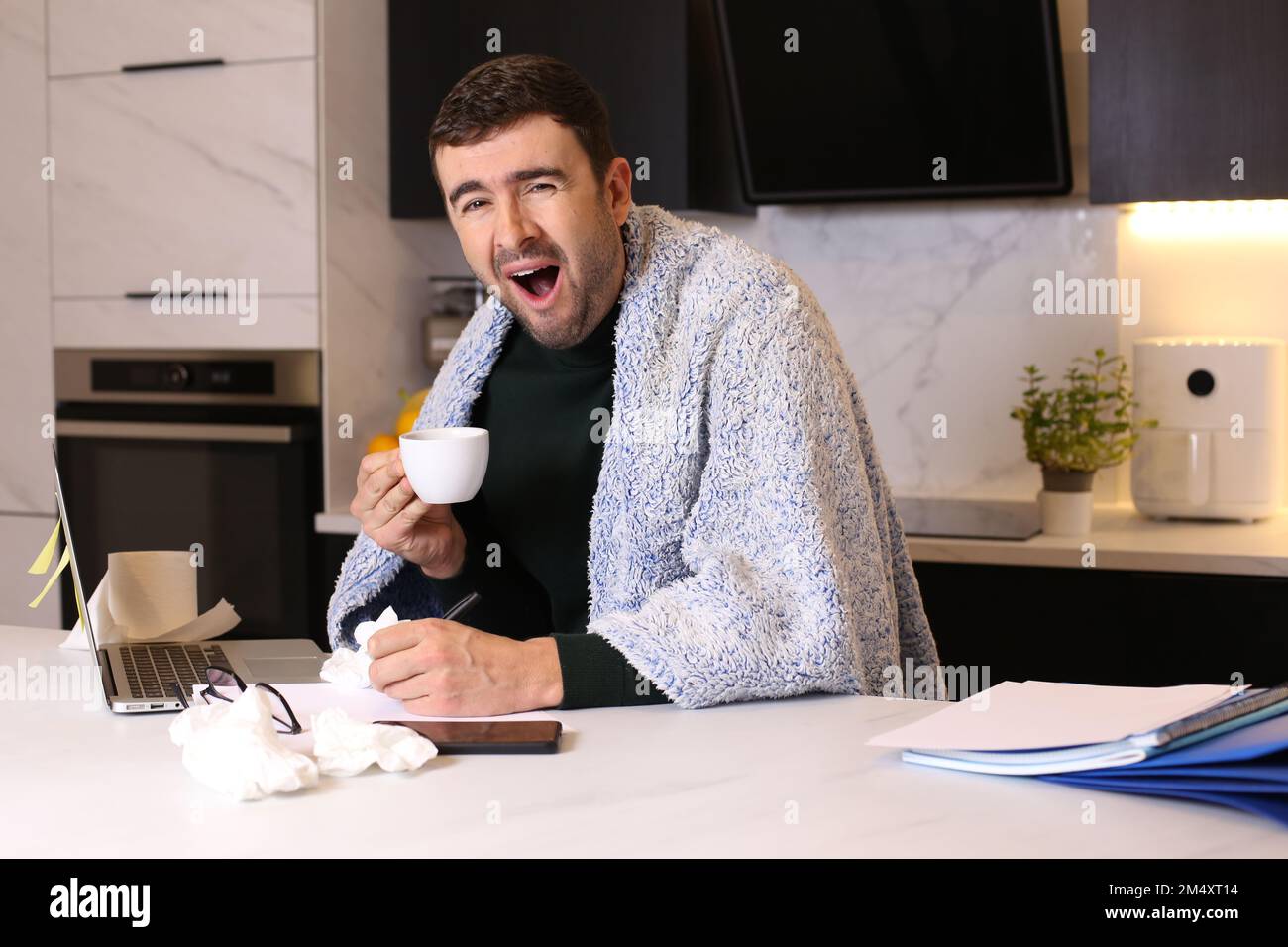 Sleepy looking man working from a cold home office Stock Photo - Alamy