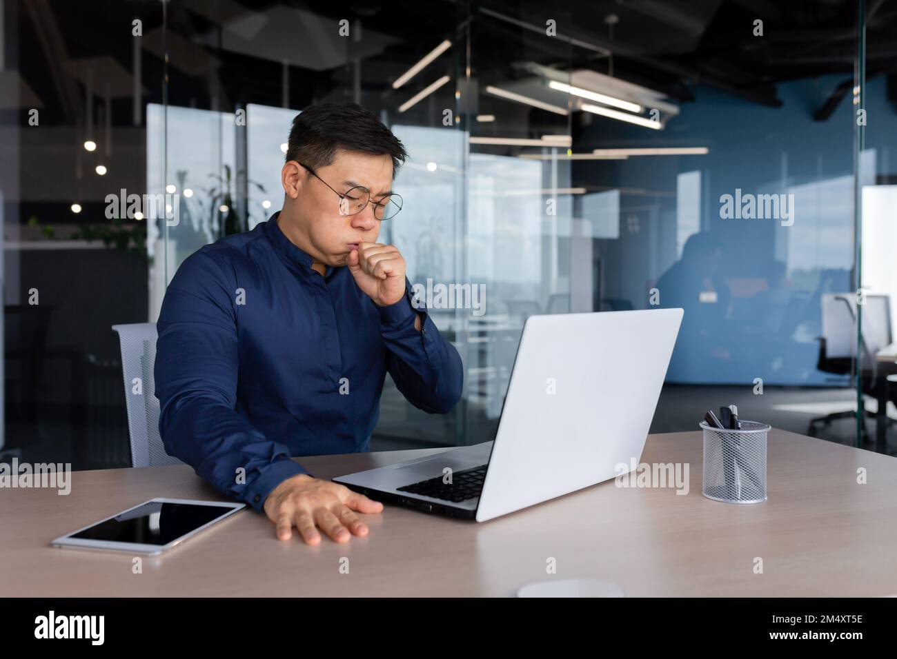 A young Asian businessman, lawyer fell ill at work. sits at the work ...
