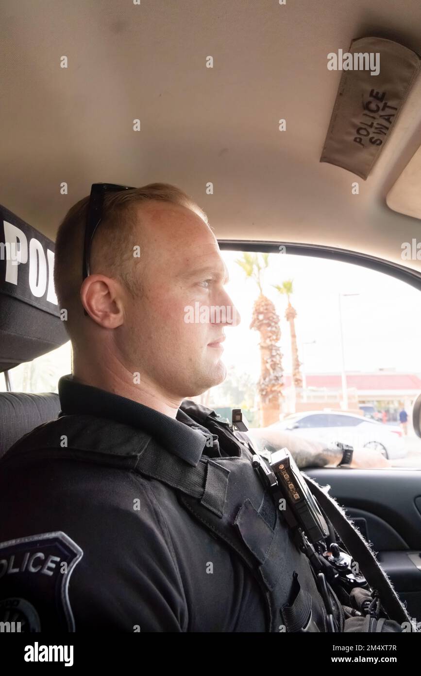Vertical image of white male caucasian police officer driving in his ...