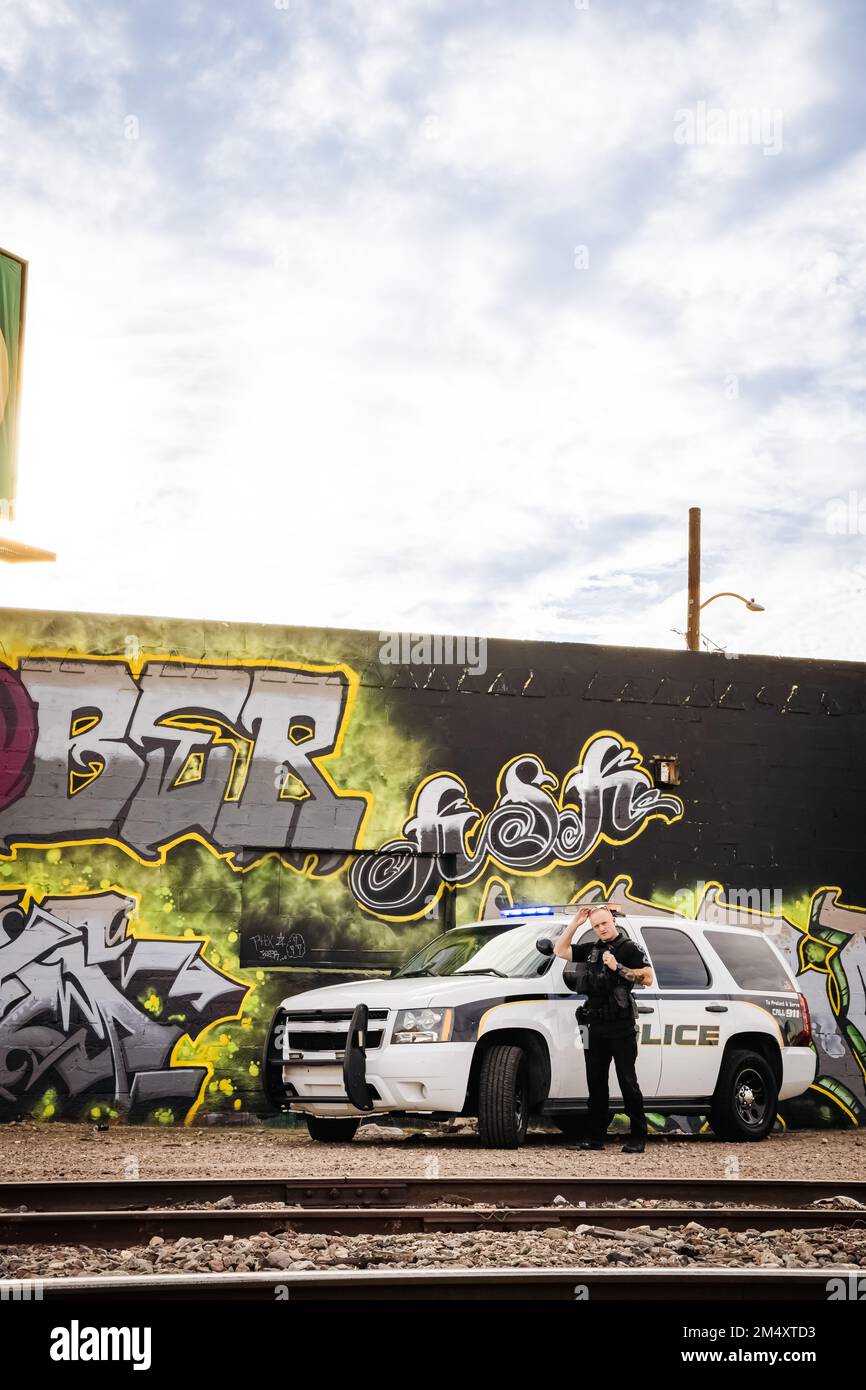 Vertical image of white male caucasian police officer posing taking off ...