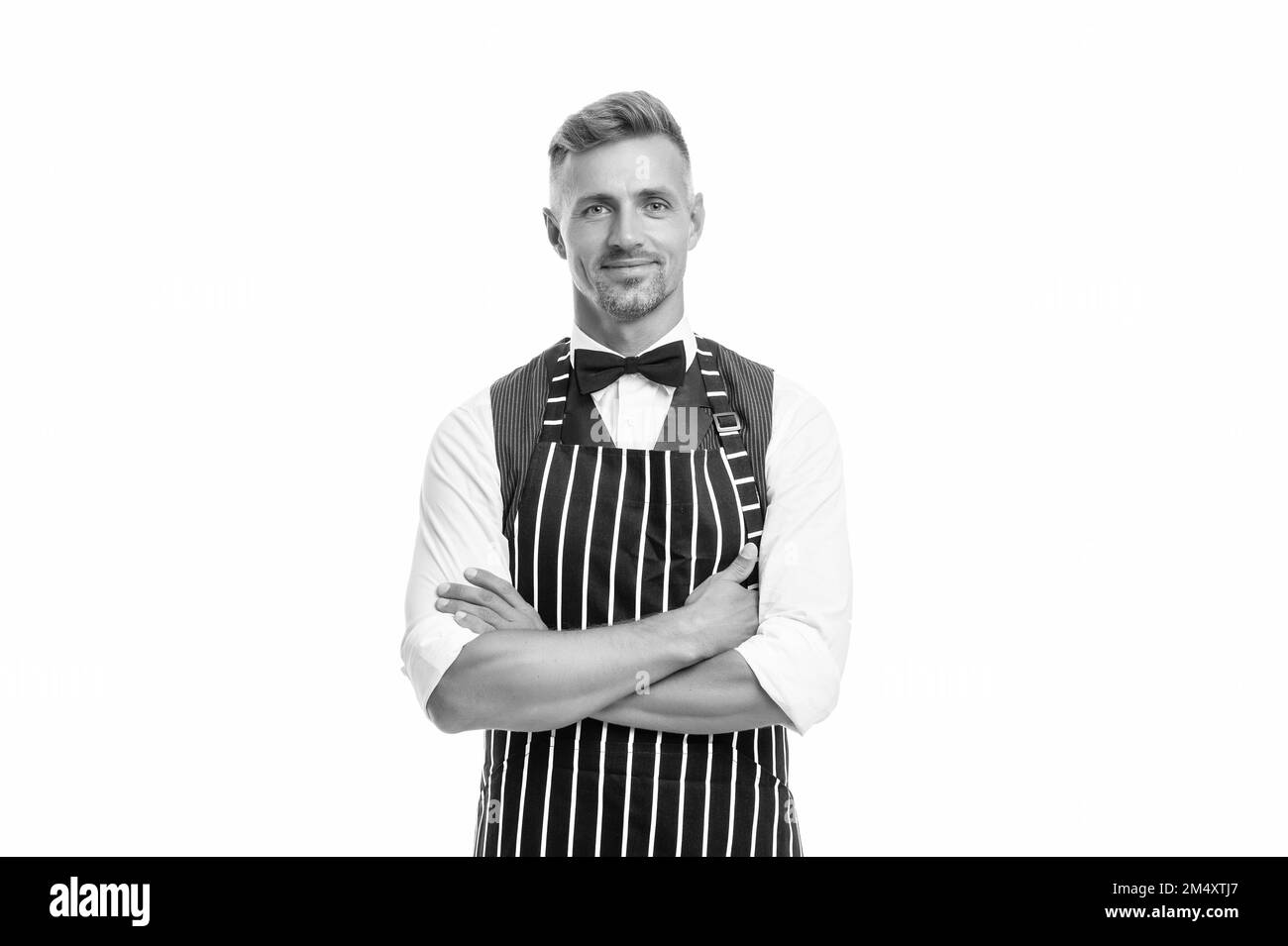 Happy chef in cook apron and bow keeping arms crossed isolated on white ...