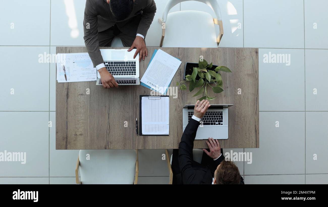 Two successful smiling businessmen are working on a laptop. view from ...