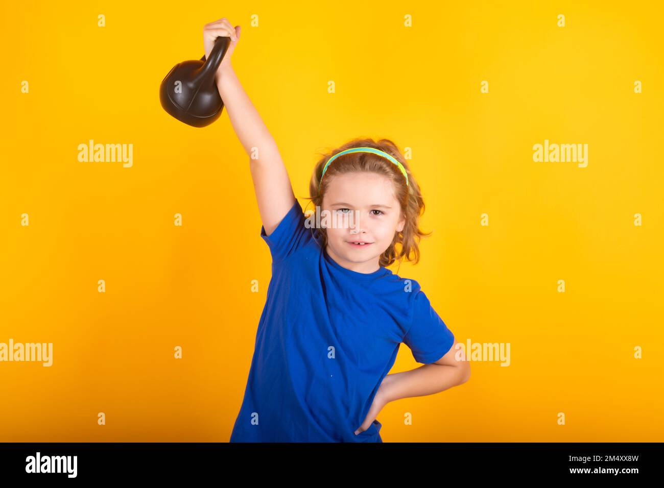 Child boy raising a kettlebell. Cute child training with dumbbells ...