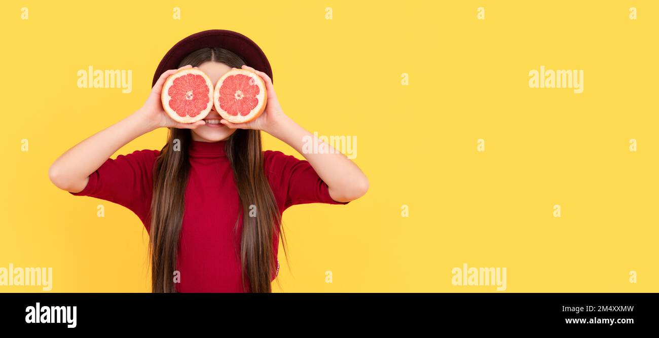 smiling kid behind grapefruit on yellow background, antioxidants. Child ...