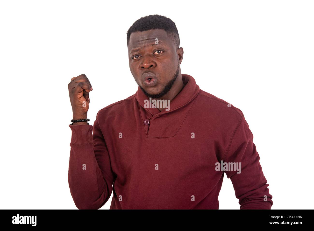 portrait of a handsome serious young man pointing thumb back while ...