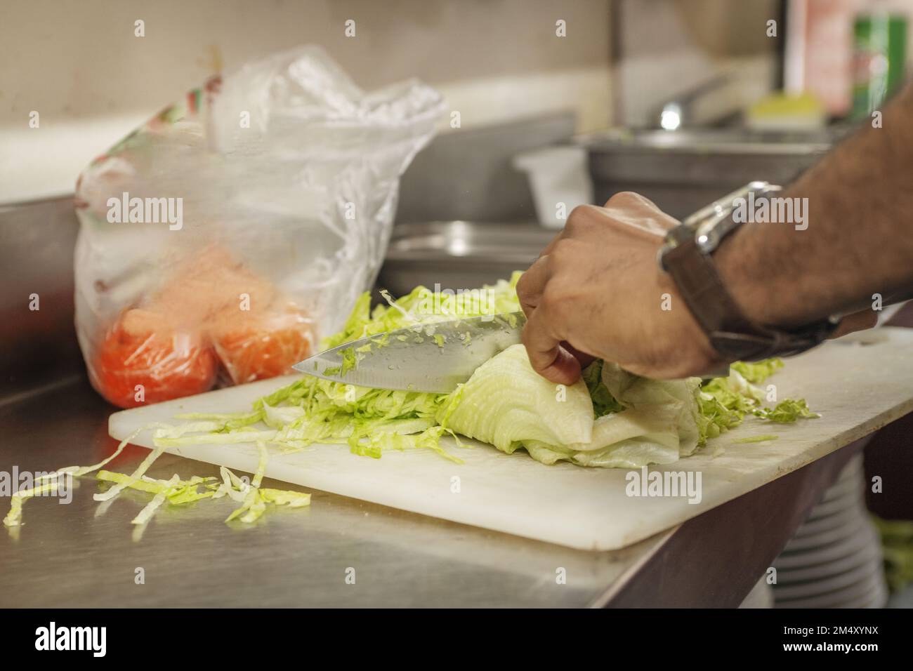 A chef chopping fresh lettuce in the kitchen to prepare a salad Stock ...