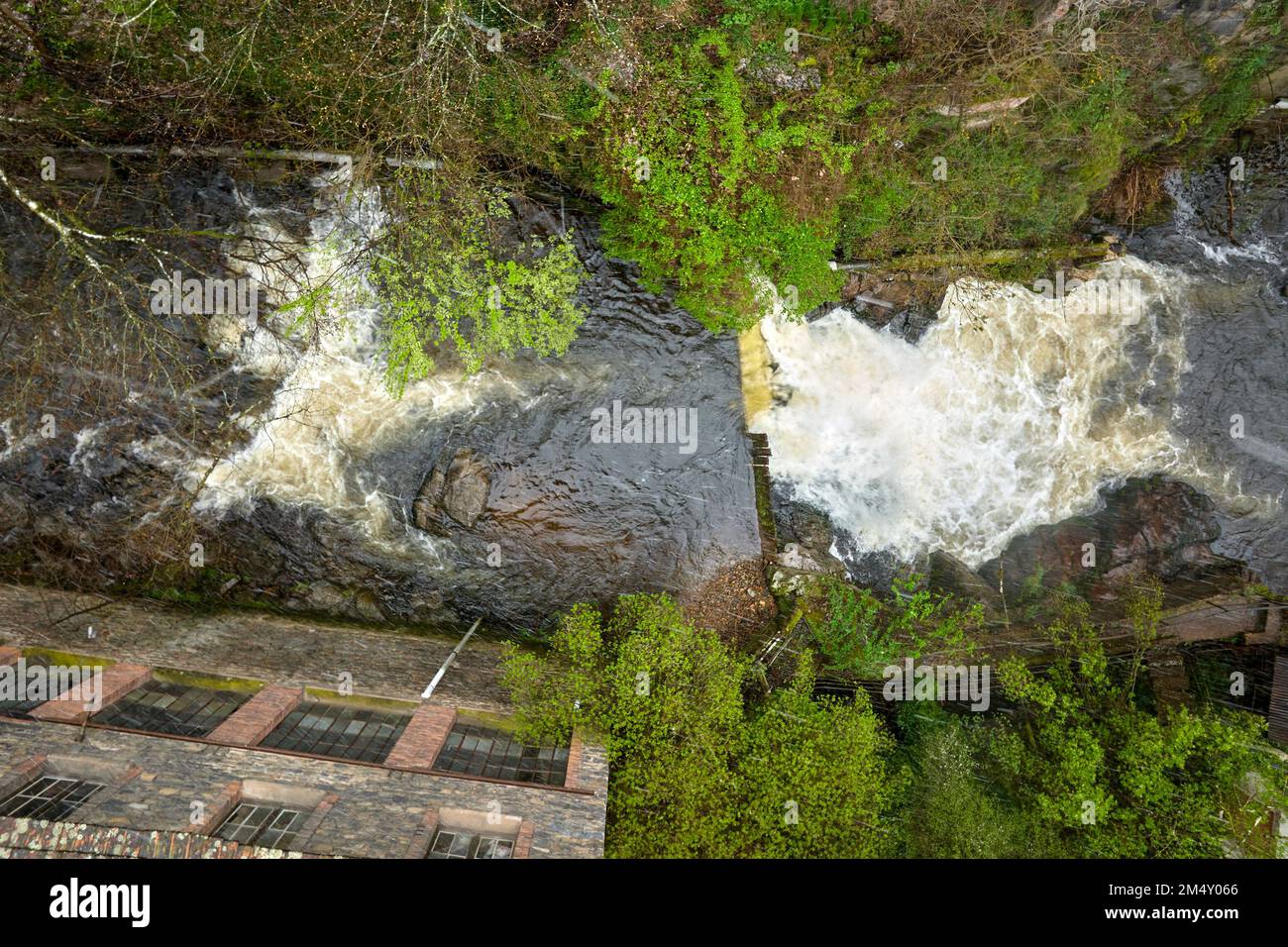 Aerial view of big mountain river with waterfall water near old factory ...